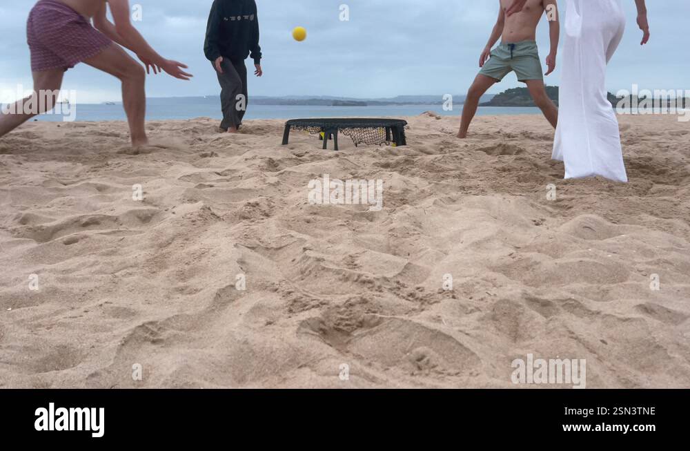 Low-angle view of a spikeball game on the beach, players in action and ...
