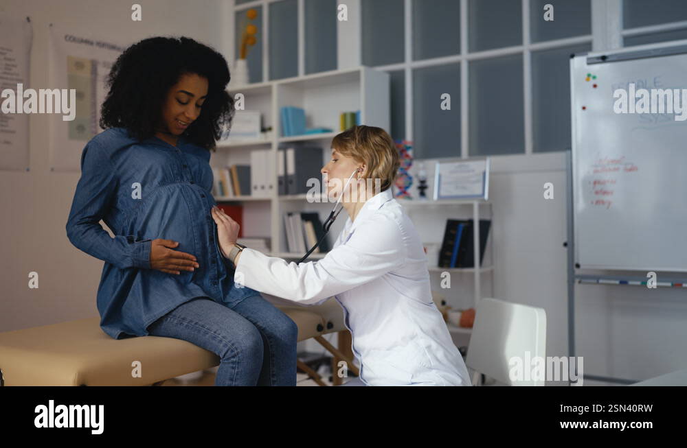 Female doctor examining pregnant woman's belly, listening to fetal ...
