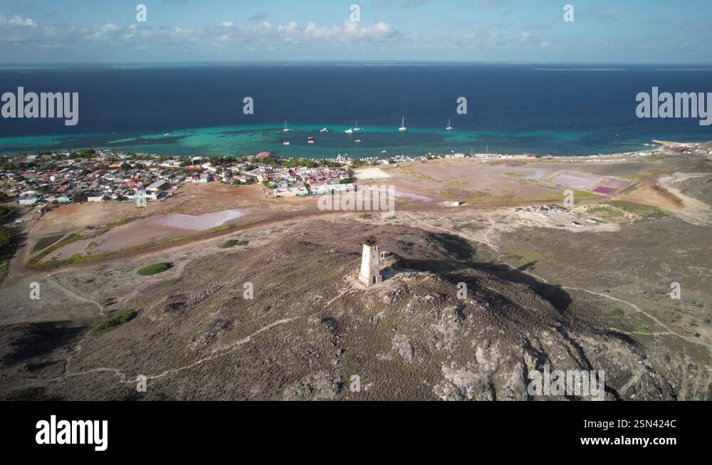 Gran roque island with a lighthouse on a hill and vibrant blue waters ...