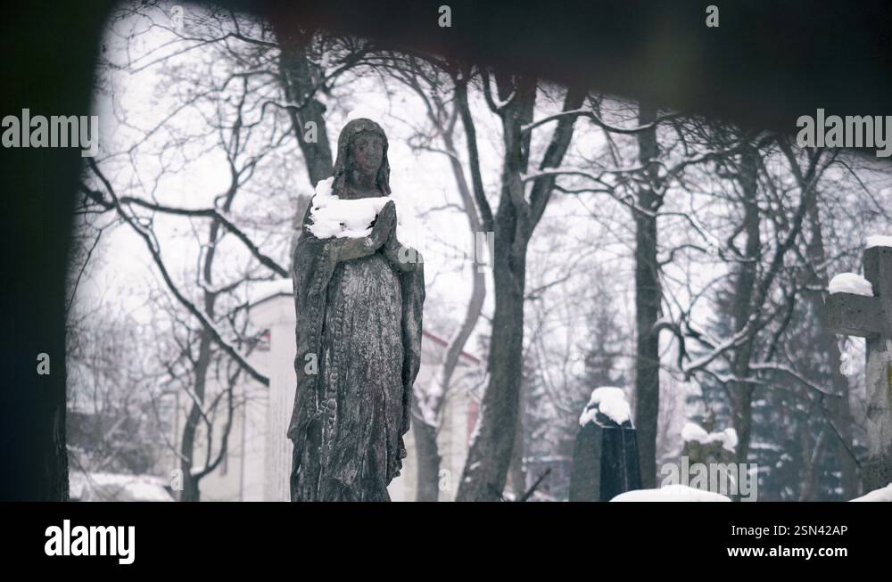 Snow covered St. Mary statue. XIX century cemetery on snowy day Stock ...