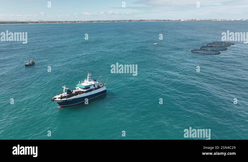 A Mid sized marine vessel tows four fish farms along the west ...