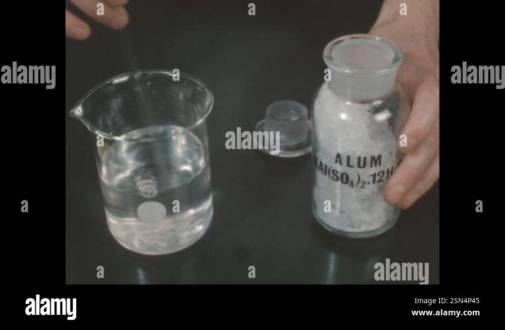 1950s: Hands stirring liquid in beaker, pouring crystals into beaker ...