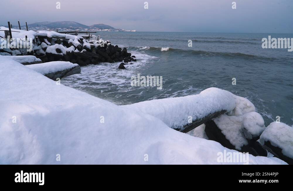 Waves crashing against the icy, snow-covered harbor Stock Video Footage ...