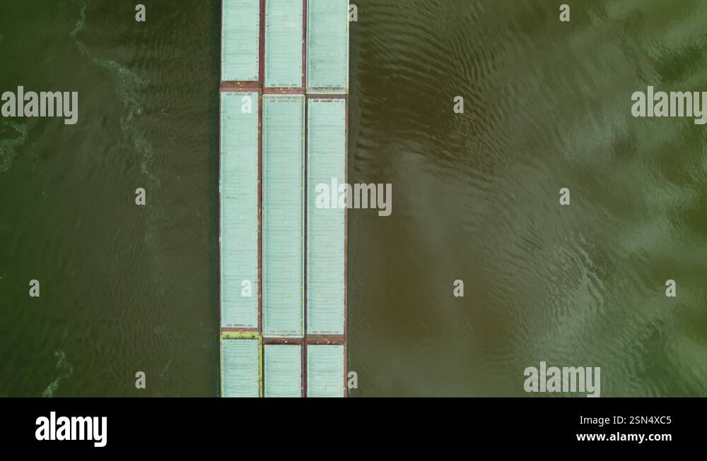Top down aerial of tugboat pushing barge, scow, floating platform on ...