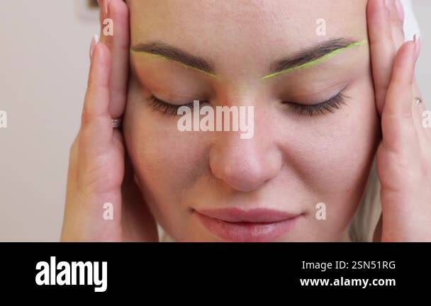 The hand of a make-up artist in black gloves applies a yellow eyebrow ...