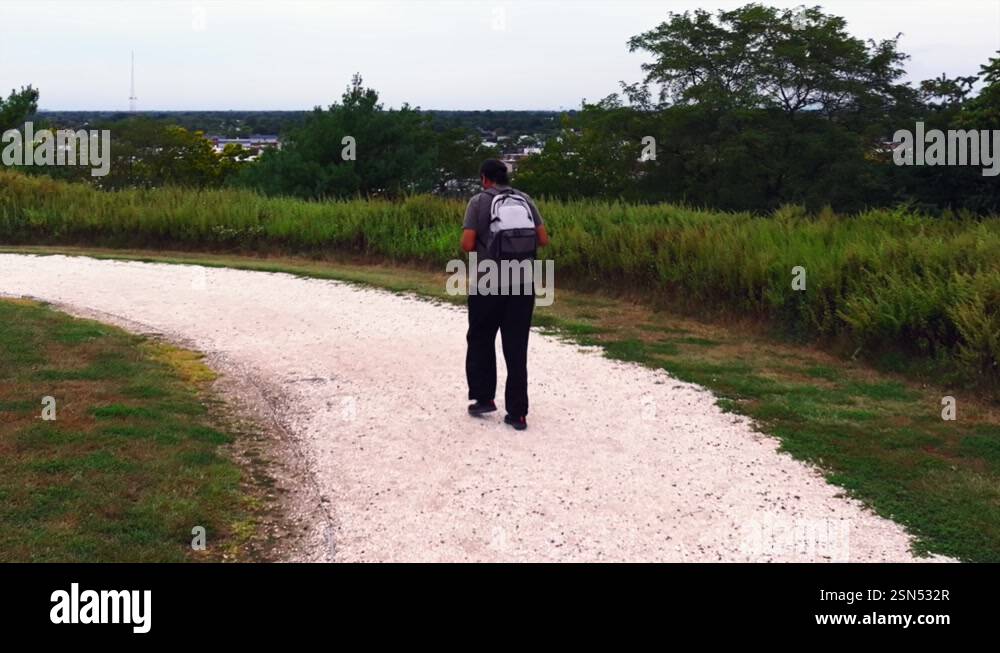 A low altitude, aerial view of a man of color walking with a backpack ...