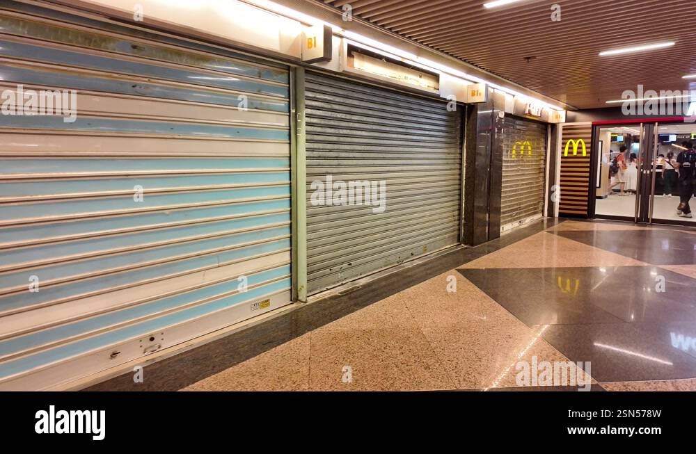 Closed storefronts with metal rolling shutters in a shopping mall ...