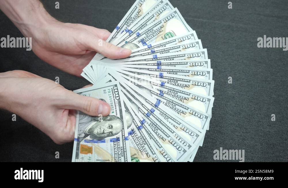 Hands carefully holding and fanning out a large stack of dollar ...