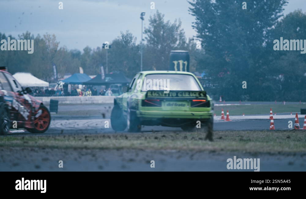 Two race cars side by side drift into frame competing on a race track ...