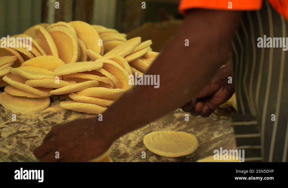 Man removing doing the final stage of the cassava galettes, grating the ...