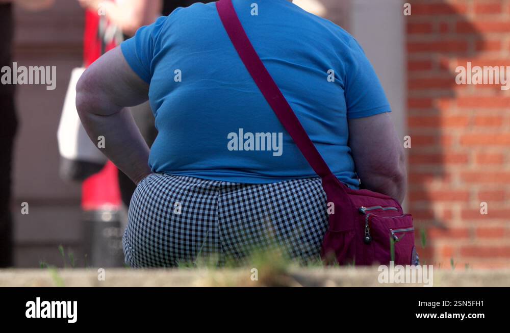 An unidentifiable fat obese person sitting down on a public street ...