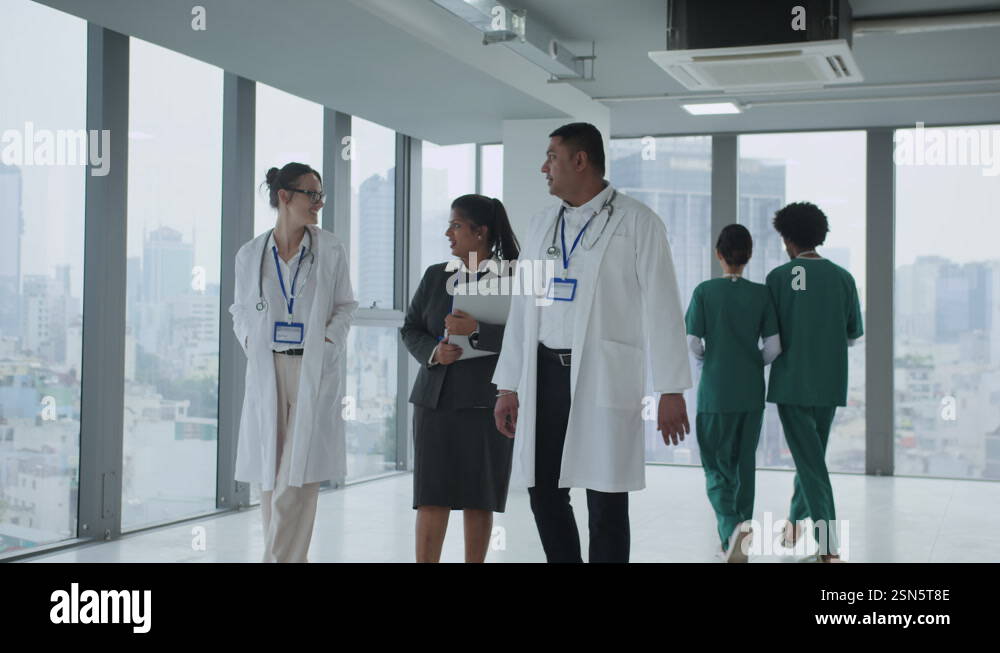 Medical Coworkers Talking while Walking along Hall of Modern Hospital ...