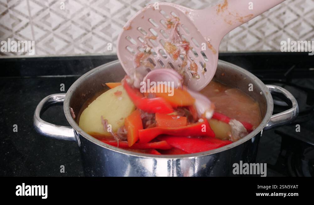 Chef combines fresh ingredients for a hearty beef stew, mixing potatoes ...