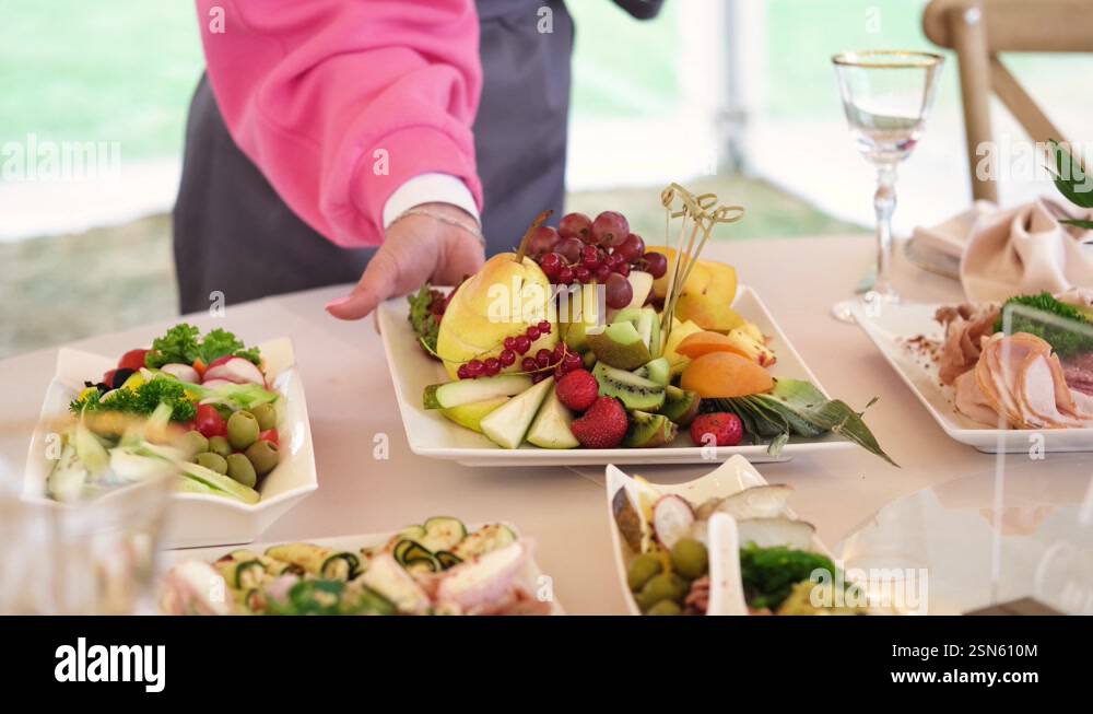Waiter placing plate of fruit on banquet table in slow motion Stock ...