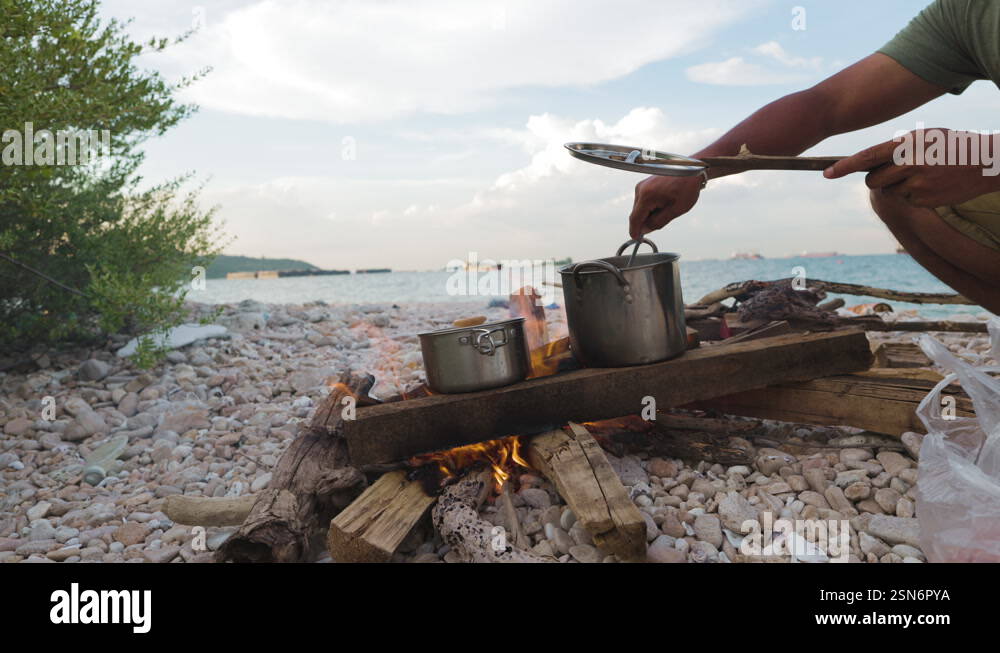 Man cooking food on camping fire outdoor recreation on island sea Stock ...