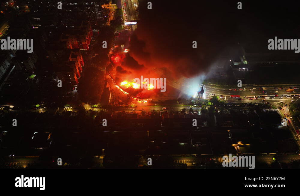 High angle drone shot around a raging building fire, nighttime in a ...