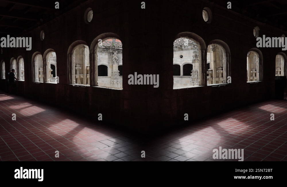 A historic stone courtyard viewed from inside through arched windows ...