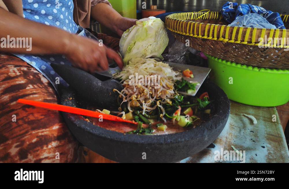 A female chef cuts fresh cabbage on a tray. Preparation for making ...