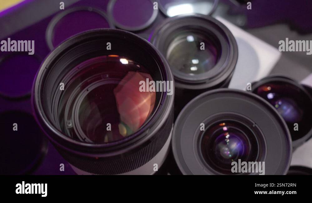 Camera lenses and filters arranged on a surface with vibrant lighting ...