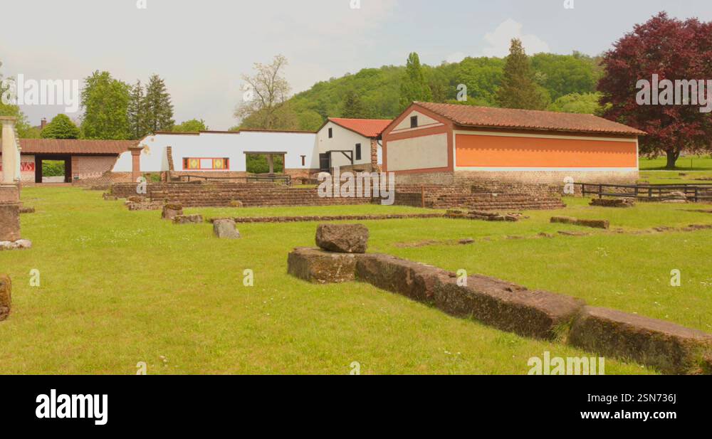 Ancient Roman ruins in green grassy area with reconstructed buildings ...