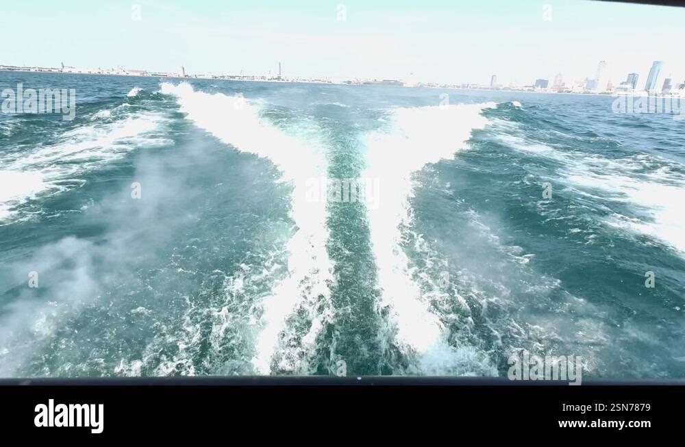 Waves ripple as water splashes from the back of a speeding boat ...