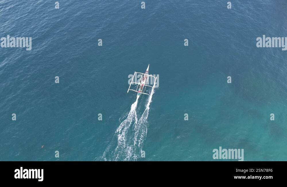 A traditional filipino banka boat cruising over clear blue ocean waters ...
