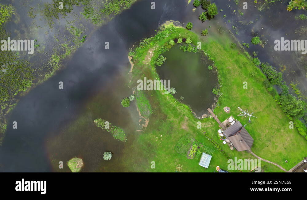 Aerial view of flooded countryside property with pond and green grassy ...