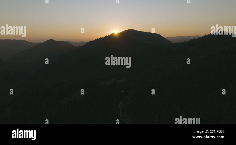 Sun appears over silhouetted mountain peak in Gifford Pinchot National ...