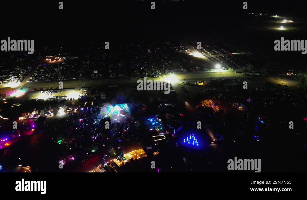 Night aerial flyover of music festival concert lights in dark city ...