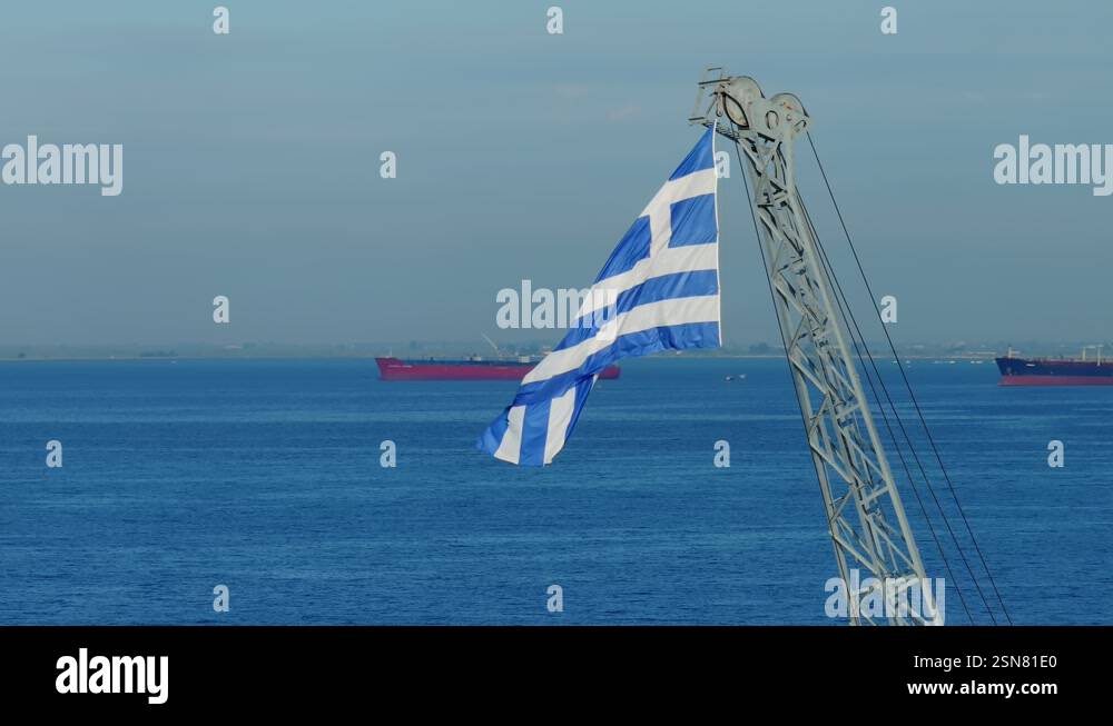 Greek flag waving with ships in the background in Thessaloniki, Greece ...