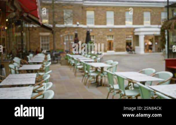 Outdoor cafe tables line a blurred london street during winter with a ...
