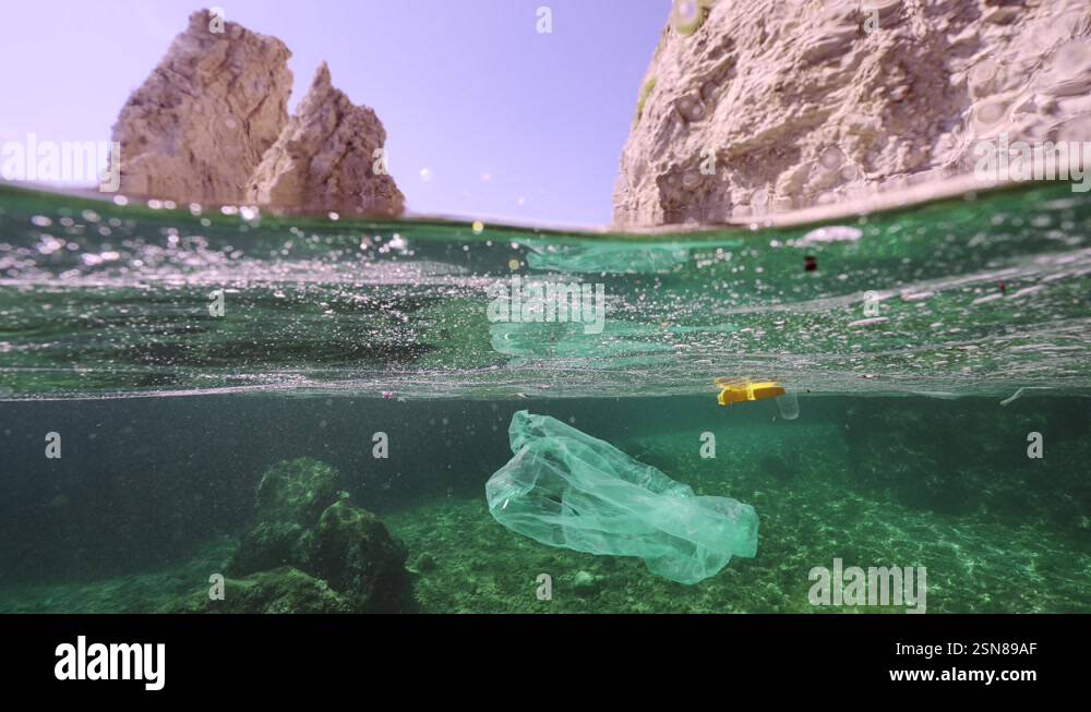 Split level, plastic and other garbage floating on surface of water ...