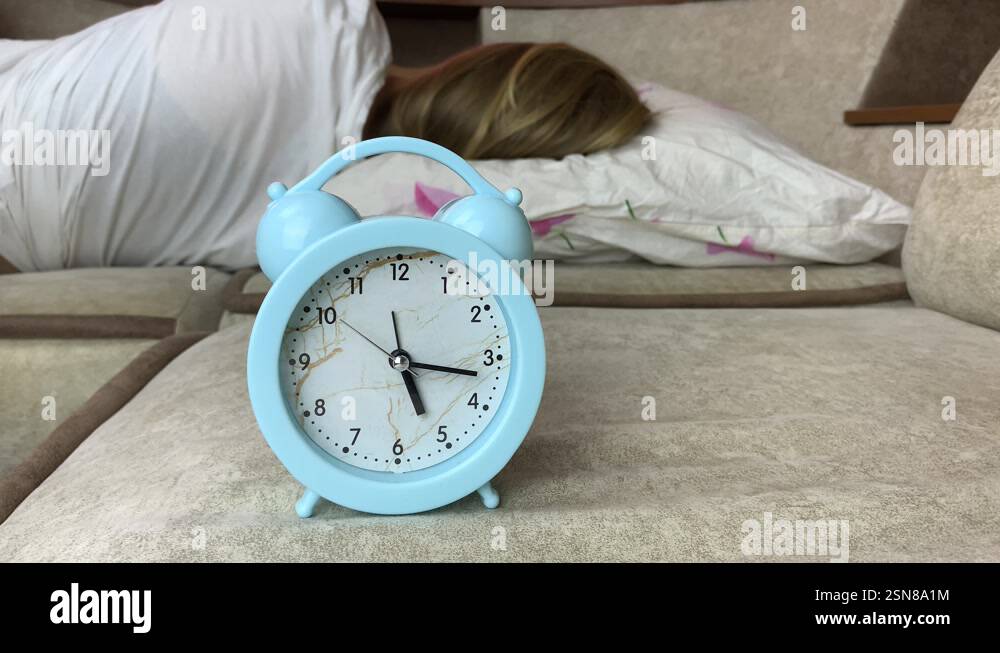 Alarm clock against background girl rotates from side to side while ...