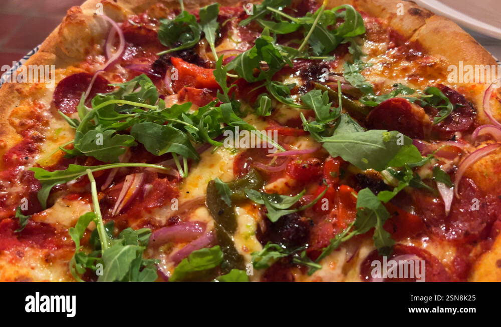 Traditional Italian spicy pepperoni pizza with red onions and rocket ...