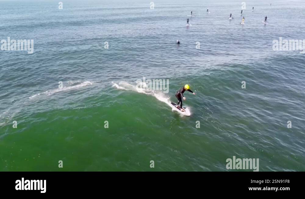 Gliding across ocean waves with a foil drive, aerial view from behind ...