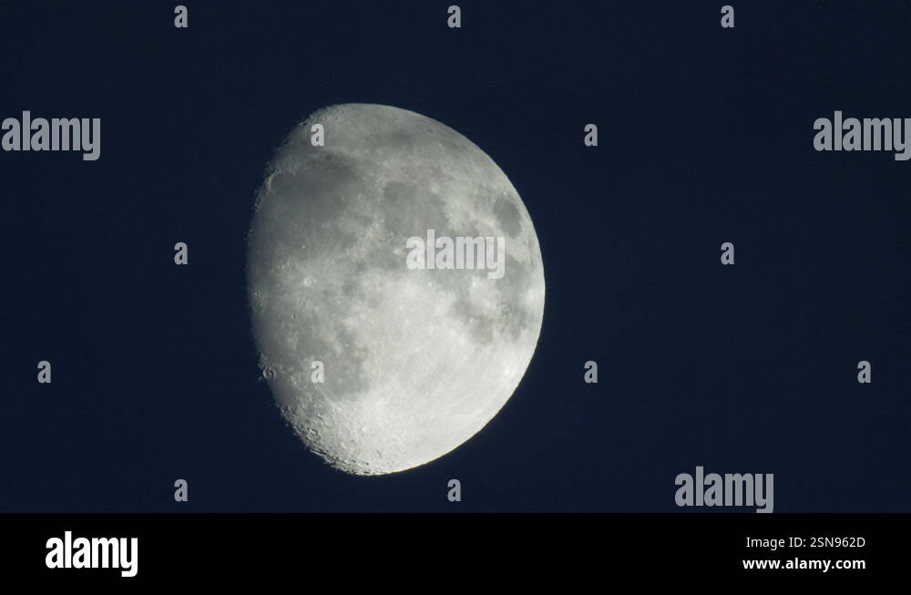 Waxing gibbous moon phase, moving over a dark blue sky with clouds ...