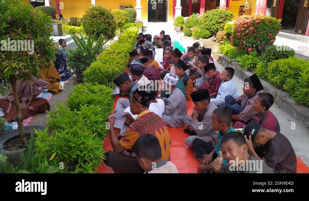 Muslim elementary school children sit together and pray in the school ...