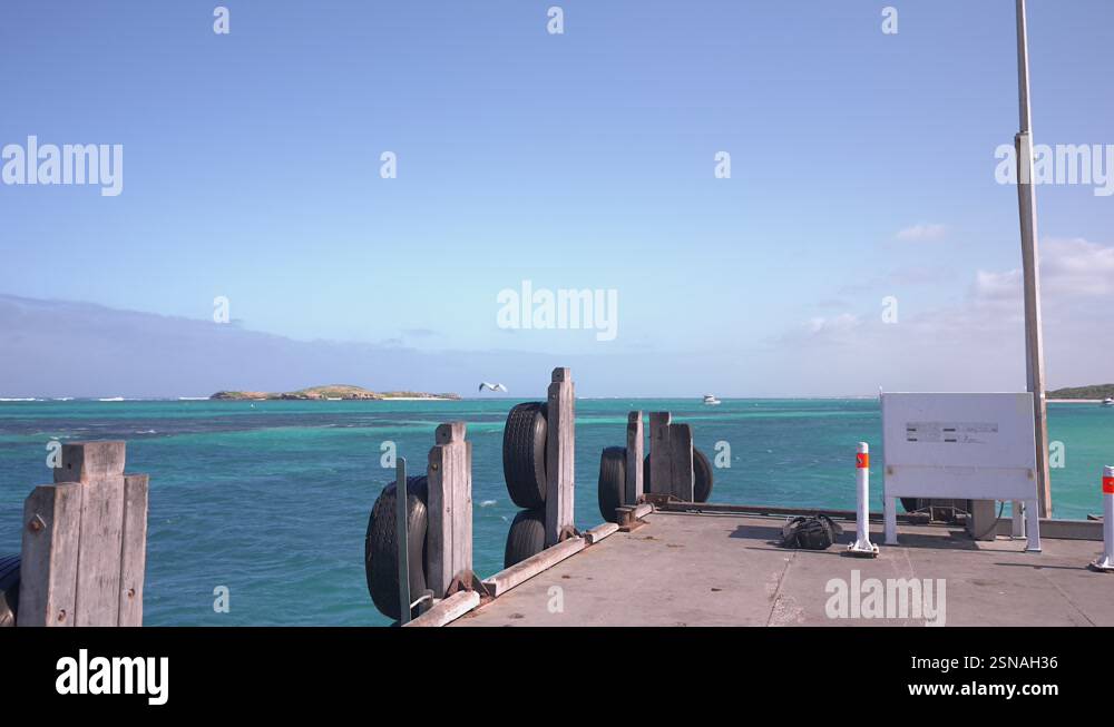 Tilt down reveal on Lancelin jetty of a strong wind blowing against a ...
