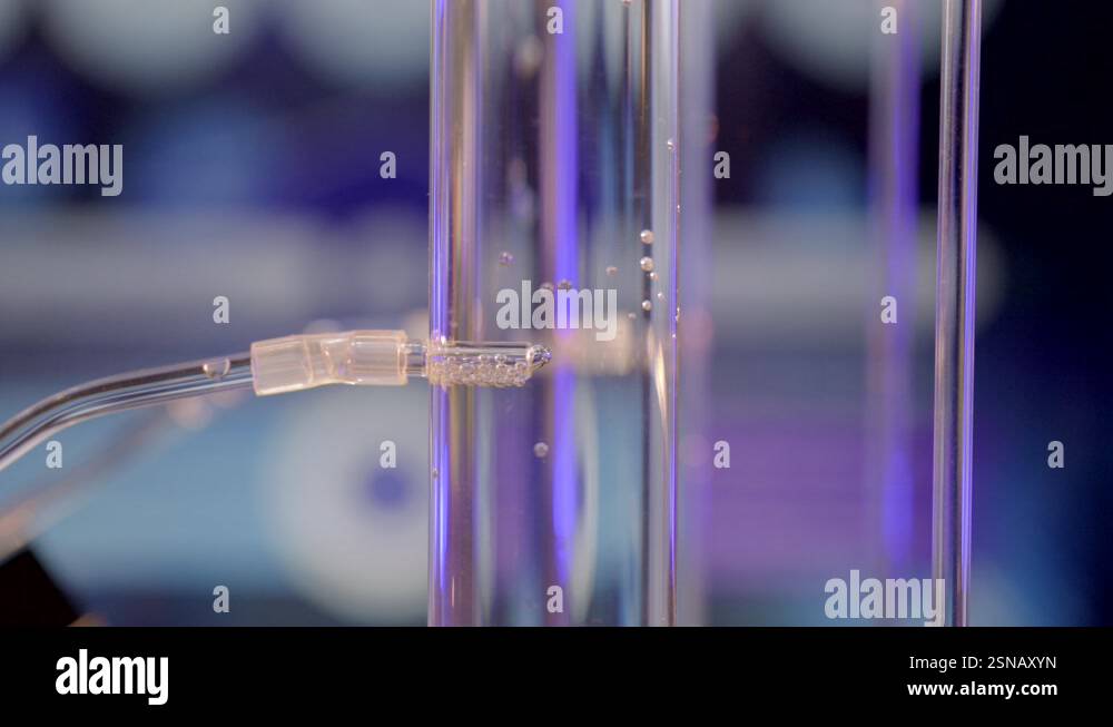 Hydrogen gas bubbles emerge from a small tube into a glass cylinder ...