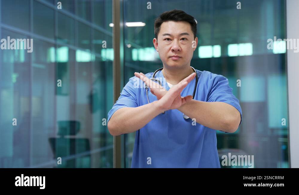 Asian doctor in blue coat showing crossed arms, X sign, waving finger ...