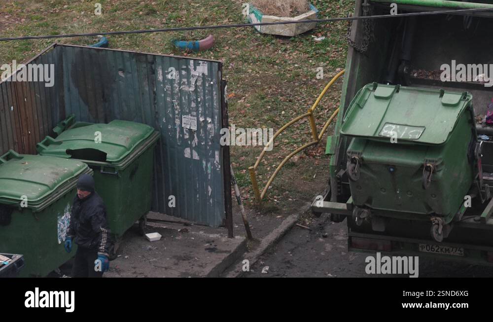 garbage workers load garbage and waste from containers into a garbage ...