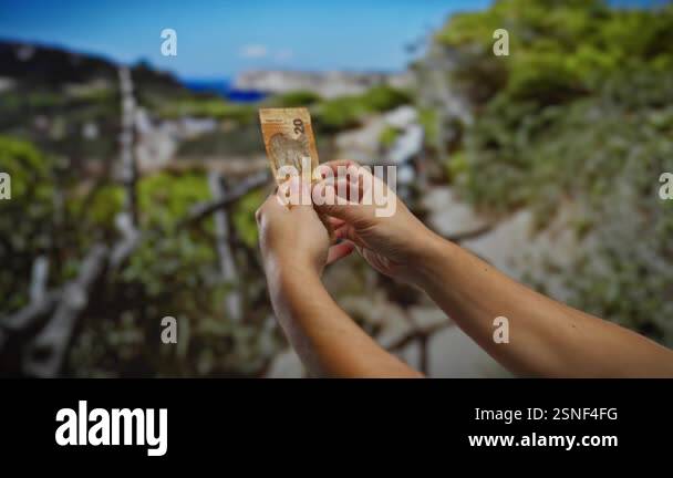 Man holding south african rand banknotes in hands at an outdoor park ...
