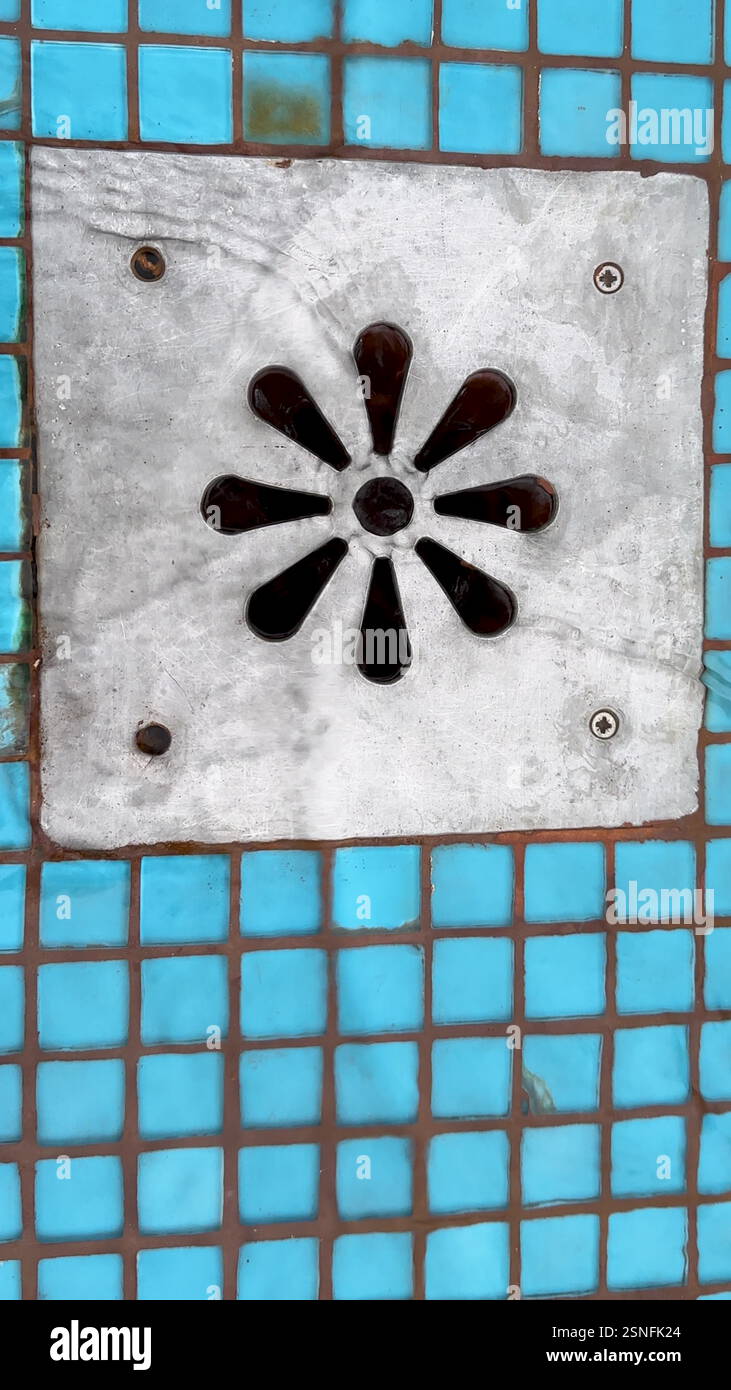 Close-up vertical footage of metallic floor drain in a blue tiled pool ...