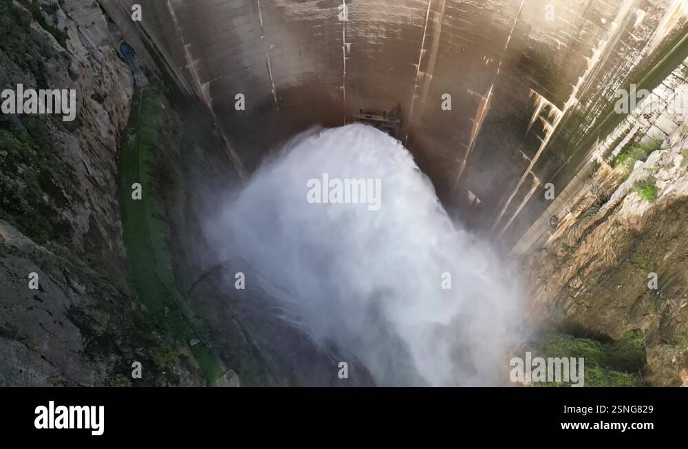Dam releasing water. Slow motion aerial view of water outlet from the ...