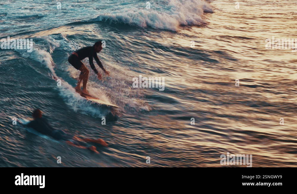 Man surfs the wave and does hand five trick by walking to the nose of ...