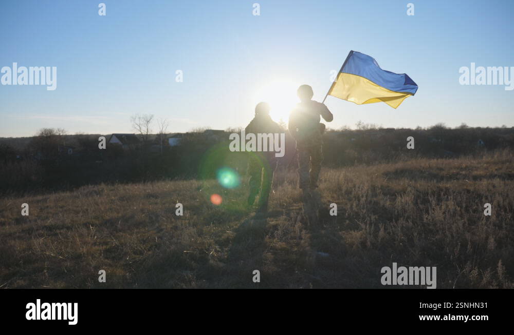 Young soldiers of ukrainian army running with lifted national banner on ...