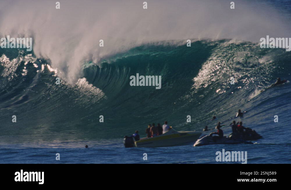 Wave crashes with mist and spray rising as surfers navigate water in ...