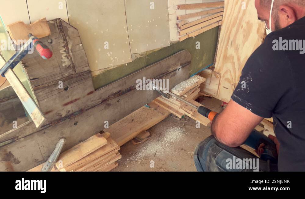 Carpenter using reciprocating saw to remove old formwork during house ...