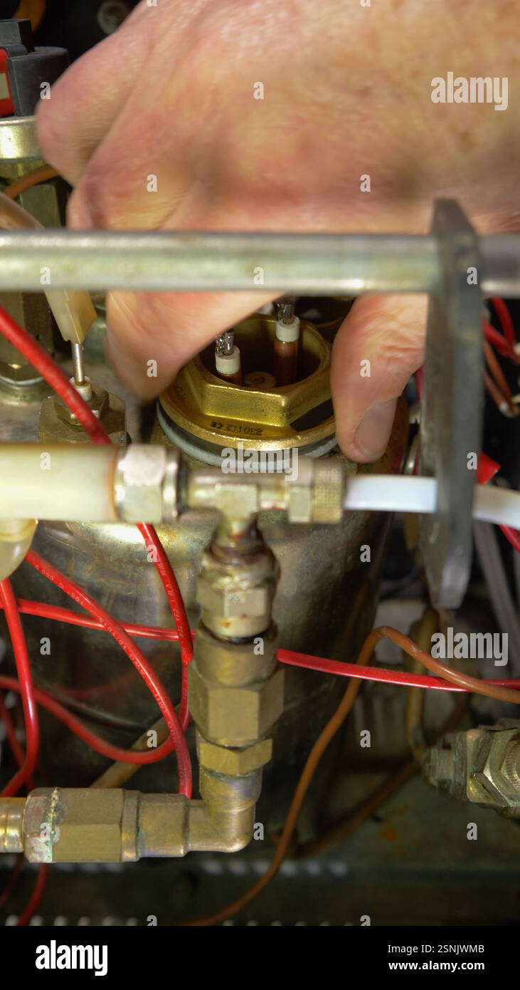 Vertical - A hand fitting a water heater element to an espresso machine ...