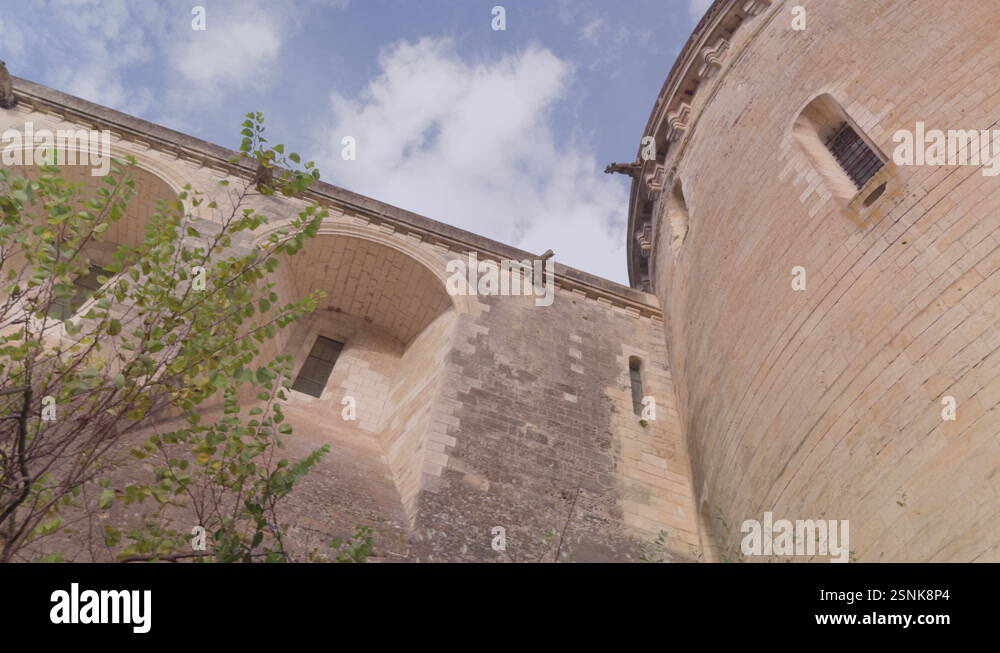 Stone arches of a historic building surrounded by greenery under a ...